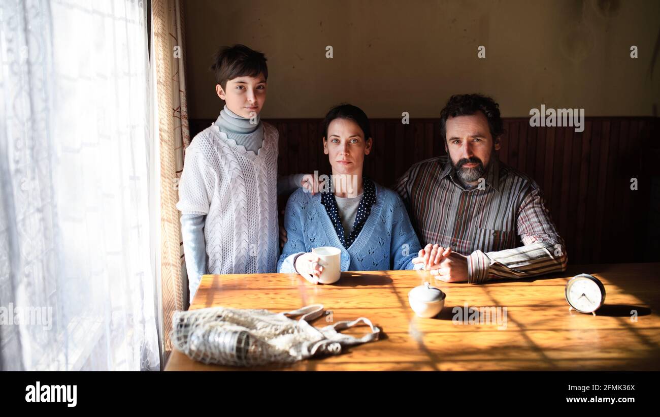 Portrait of poor mature couple with small daughter indoors at home ...