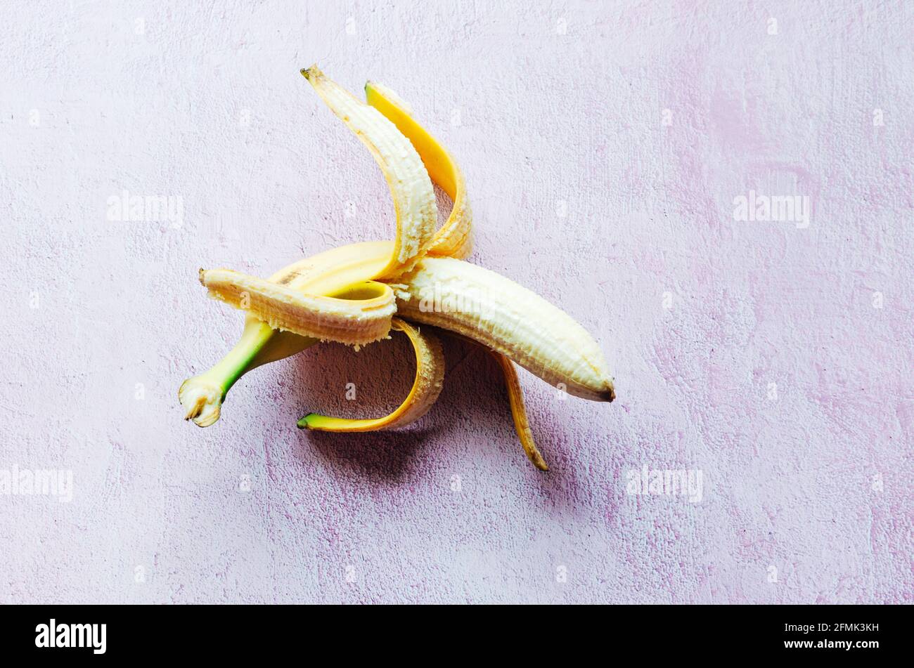 Half open banana on pink textured background Stock Photo - Alamy