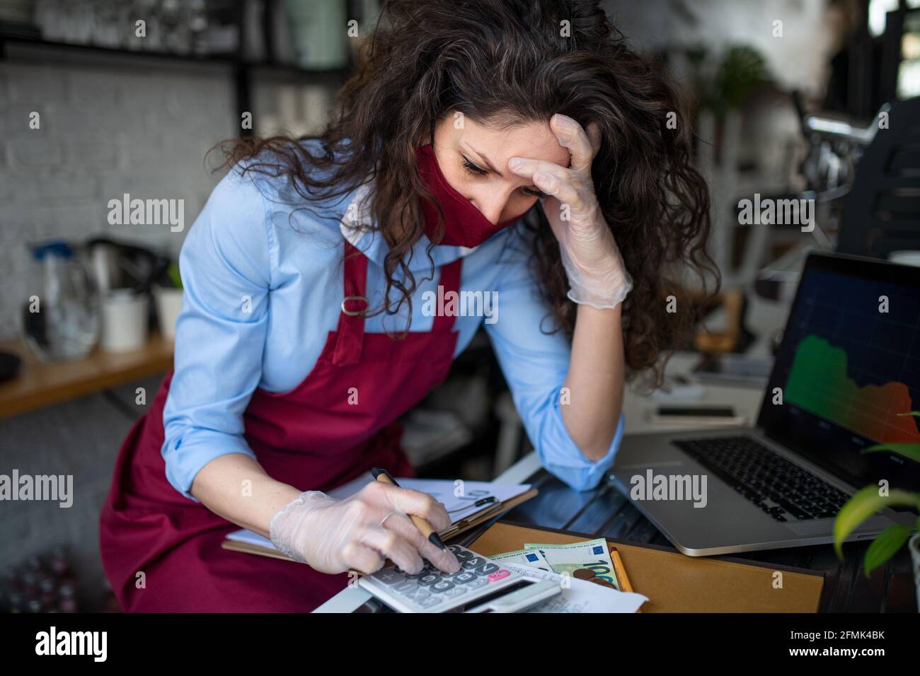 Frustrated coffee shop manager calculating figures in cafe, small ...