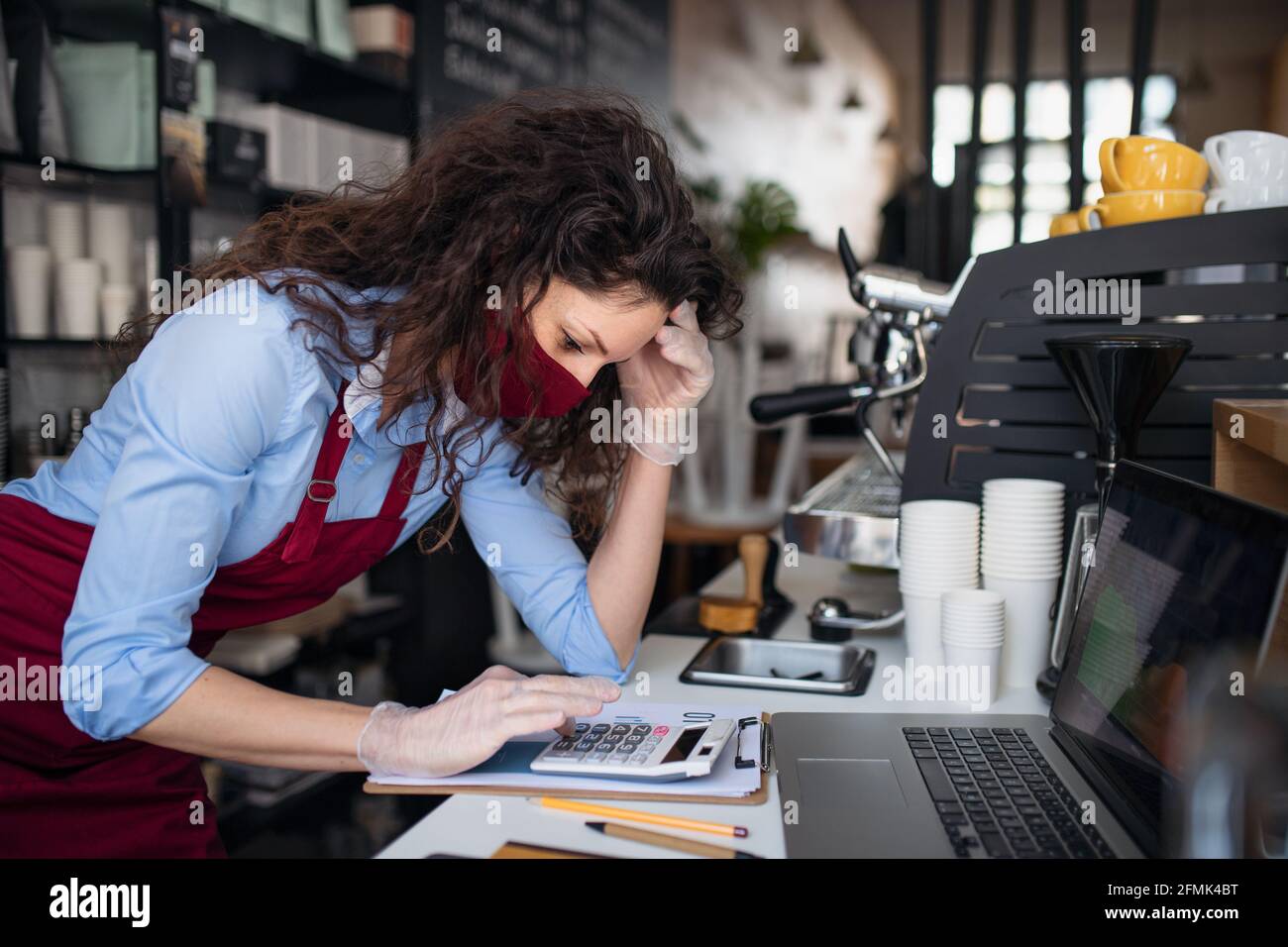 Frustrated coffee shop manager calculating figures in cafe, small ...