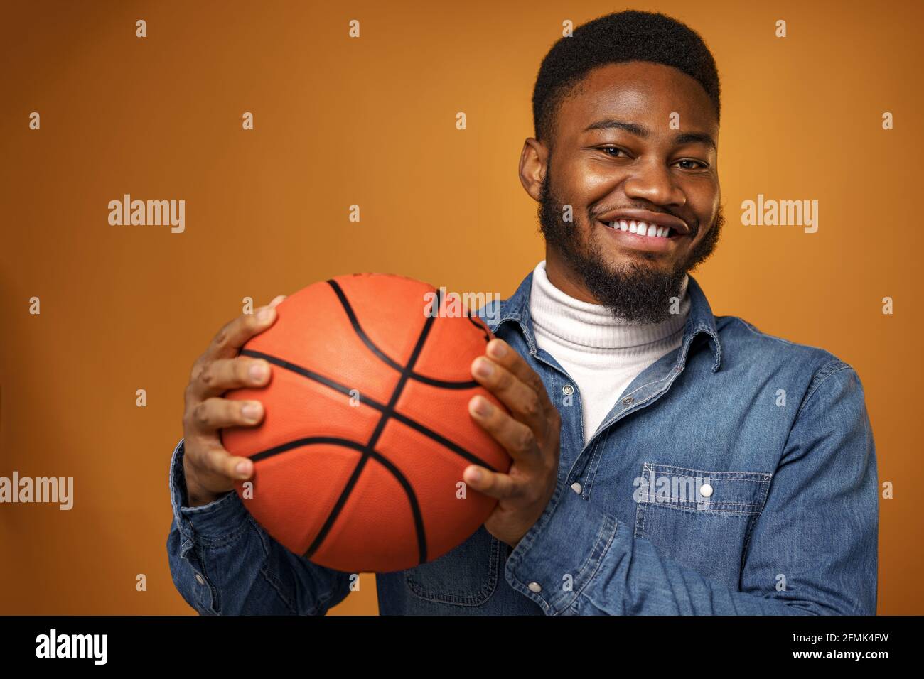 African american man holding basketball ball and looking at camera on ...