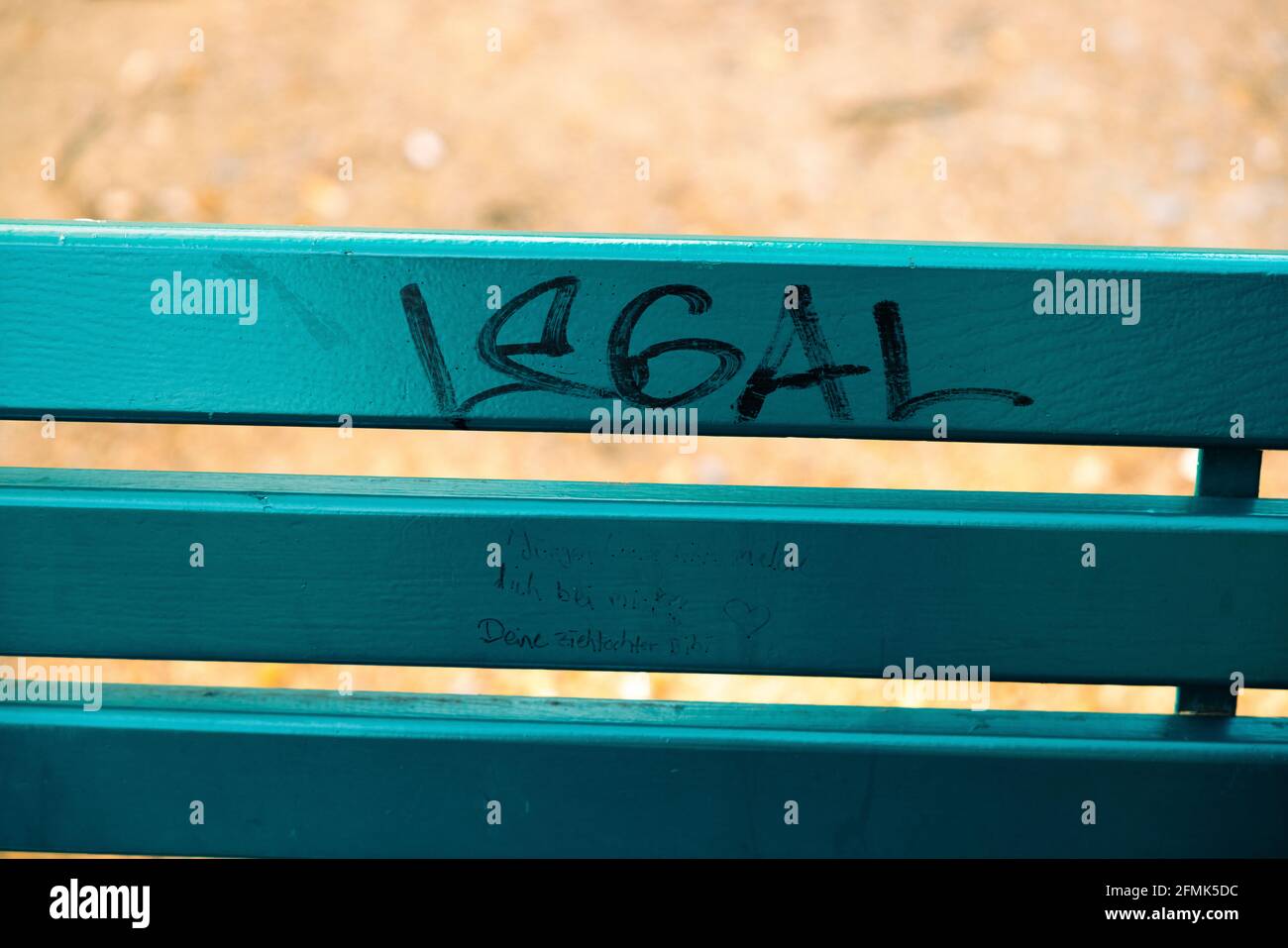 Closeup of a park bench with a lettering "LEGAL" on it; street art and ...