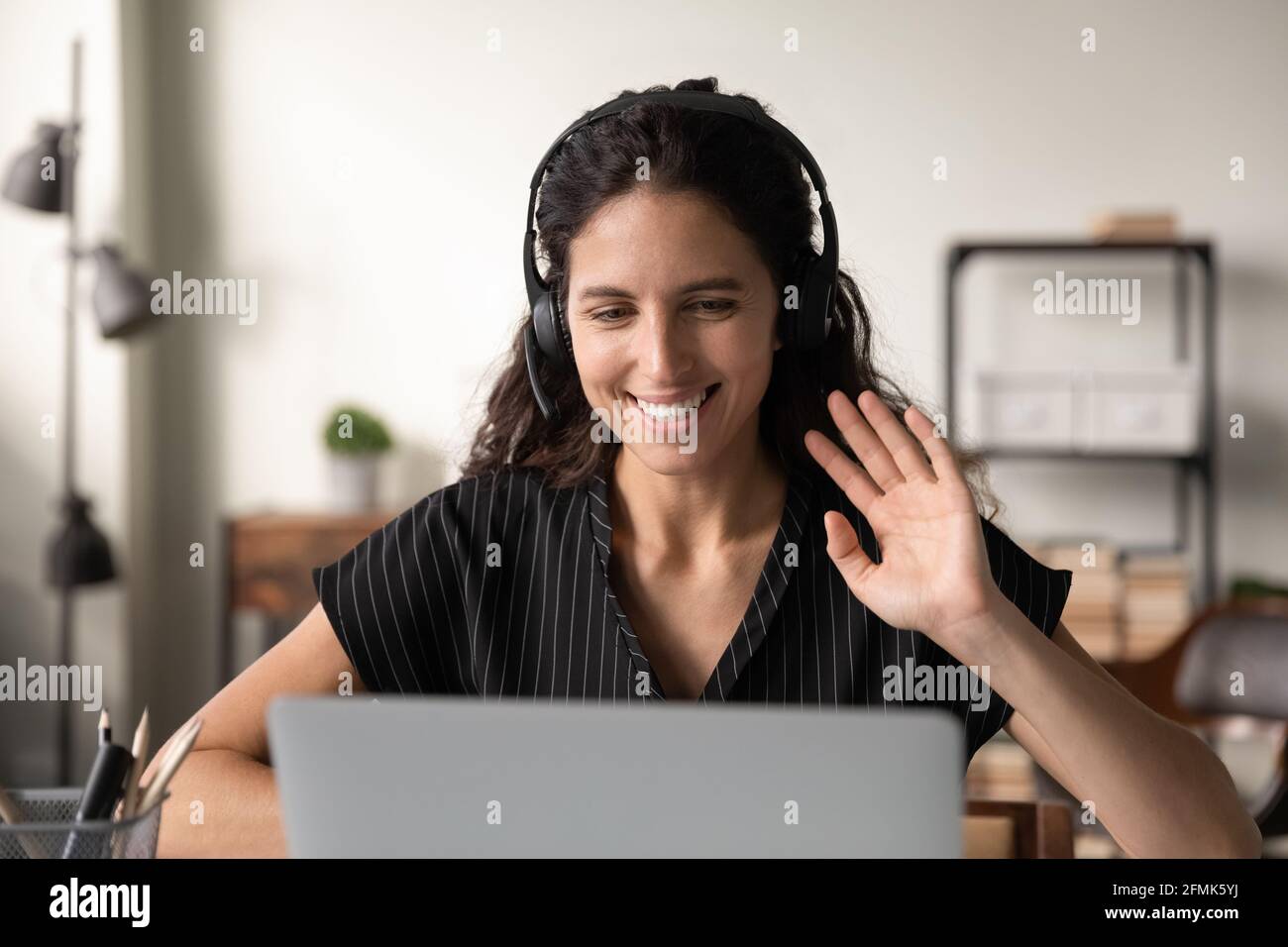 Polite latin female wear headset attend virtual conference greeting ...