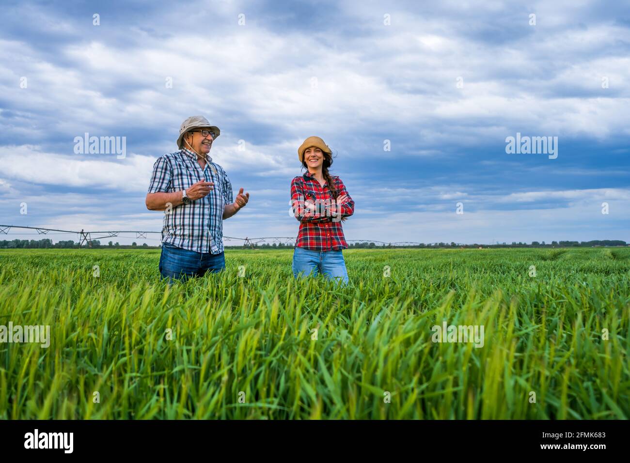 Proud two generations farmers are standing in their barley field and ...