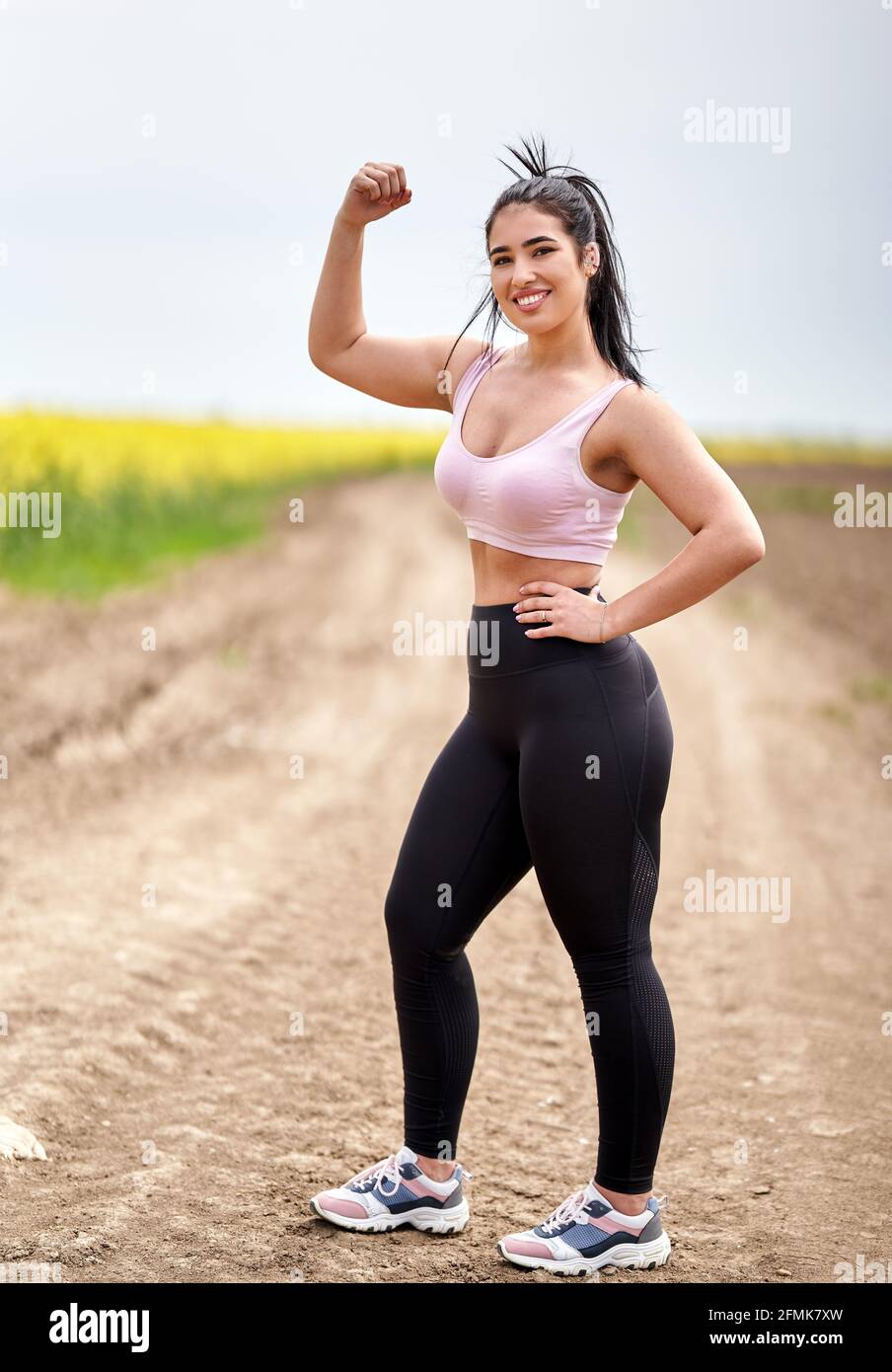 Plus size female runner posing in running outfit on a dirt road by a ...