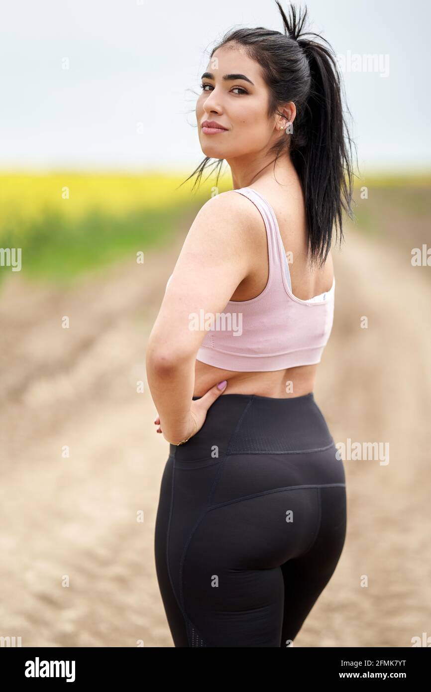 Plus size female runner posing in running outfit on a dirt road by a ...