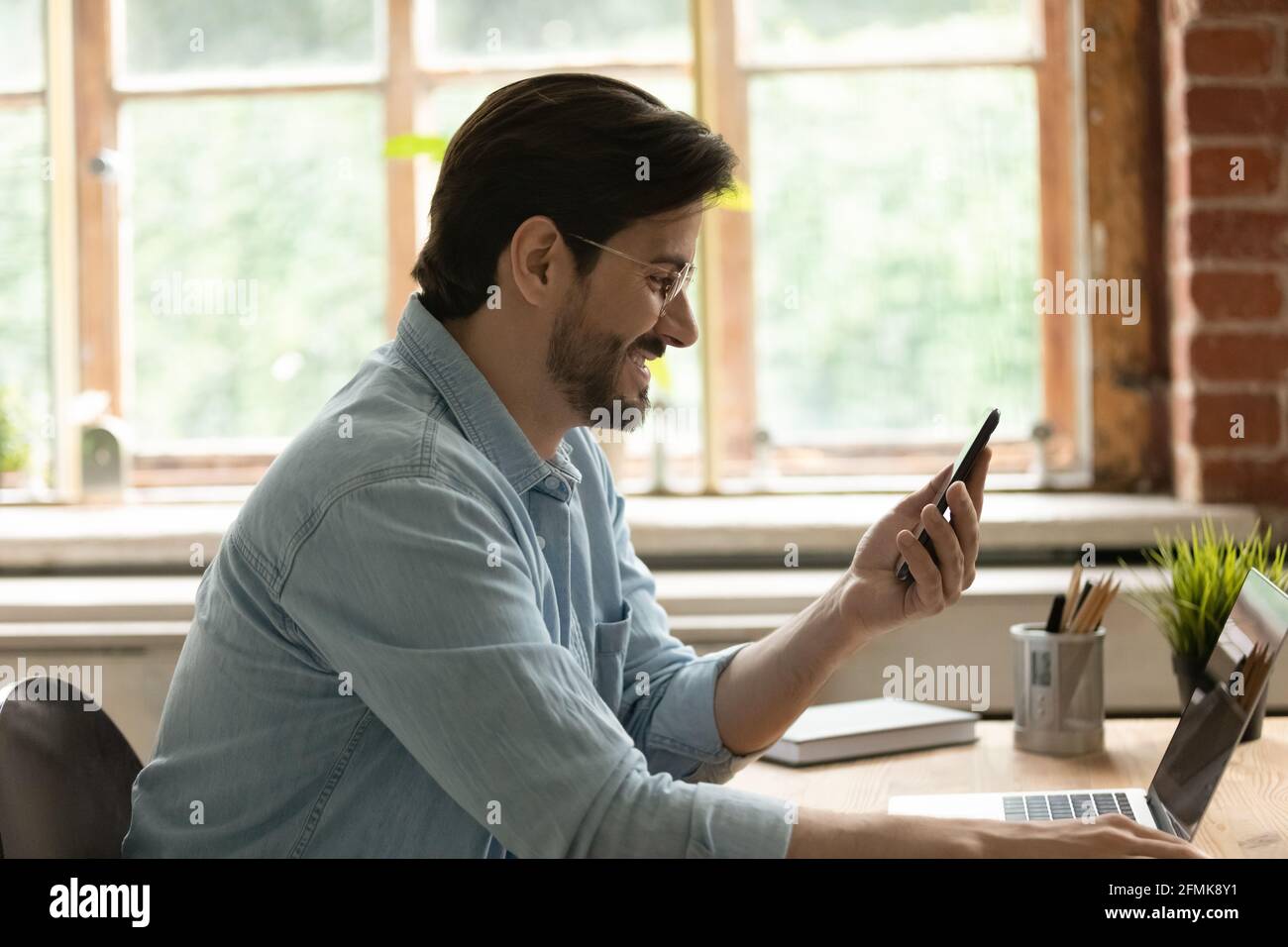 Side view smiling man in glasses looking at phone screen Stock Photo ...