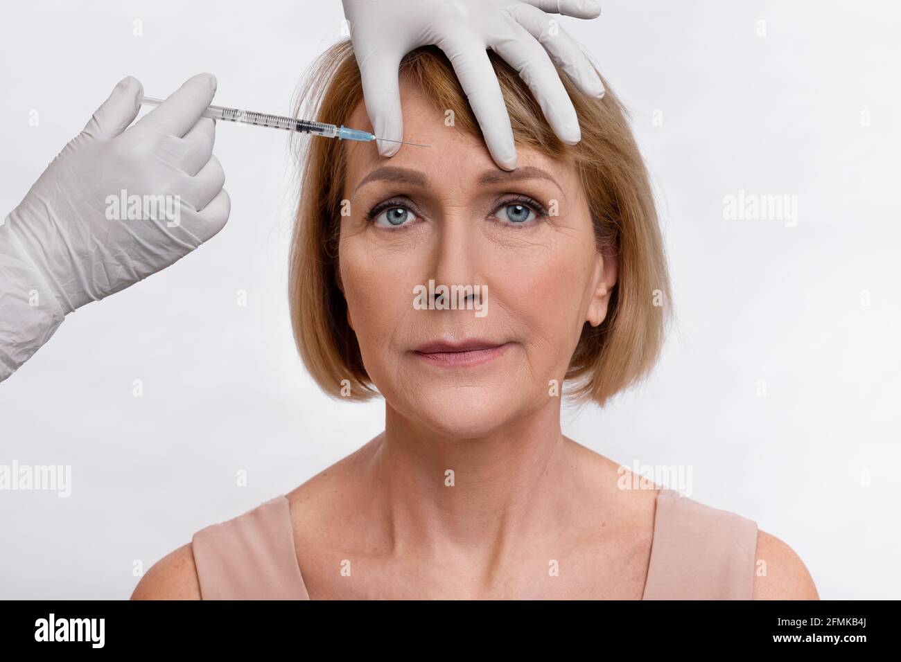 Charming mature woman getting beauty facial injections from ...