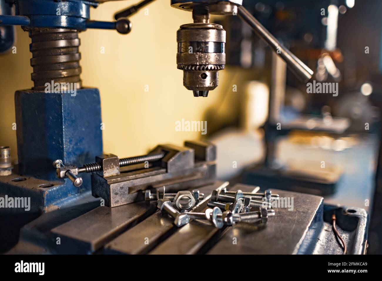 Metal chrome bolts and nuts lie on the drilling machine at the ...