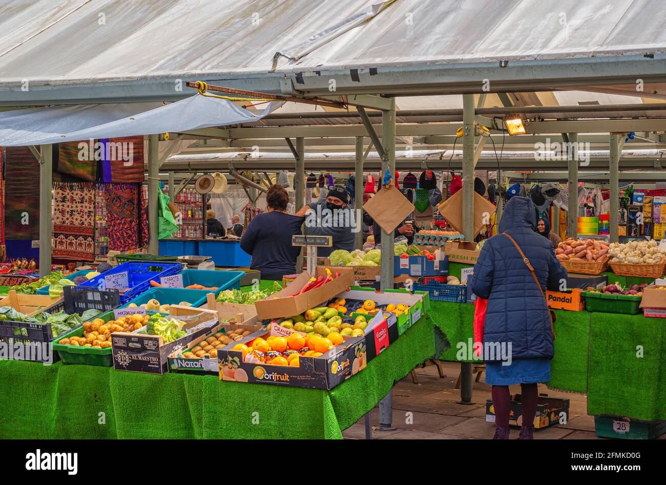 Market stall selling fruit and vegetables. A customer waits to be ...