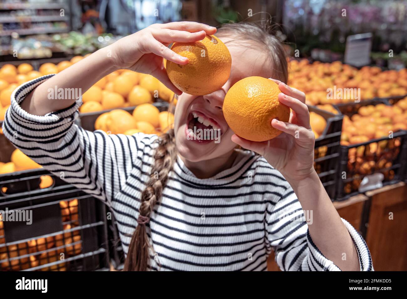Cheerful little girl posing with oranges in a grocery store Stock Photo ...
