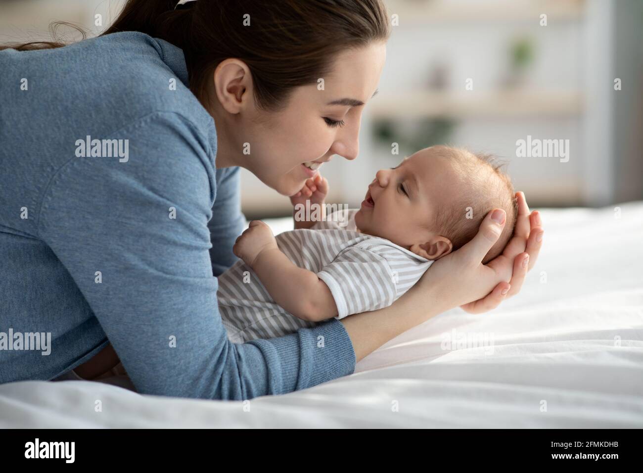 Joy Of Motherhood. Happy Smiling Young Mom Relaxing In Bed With Her ...