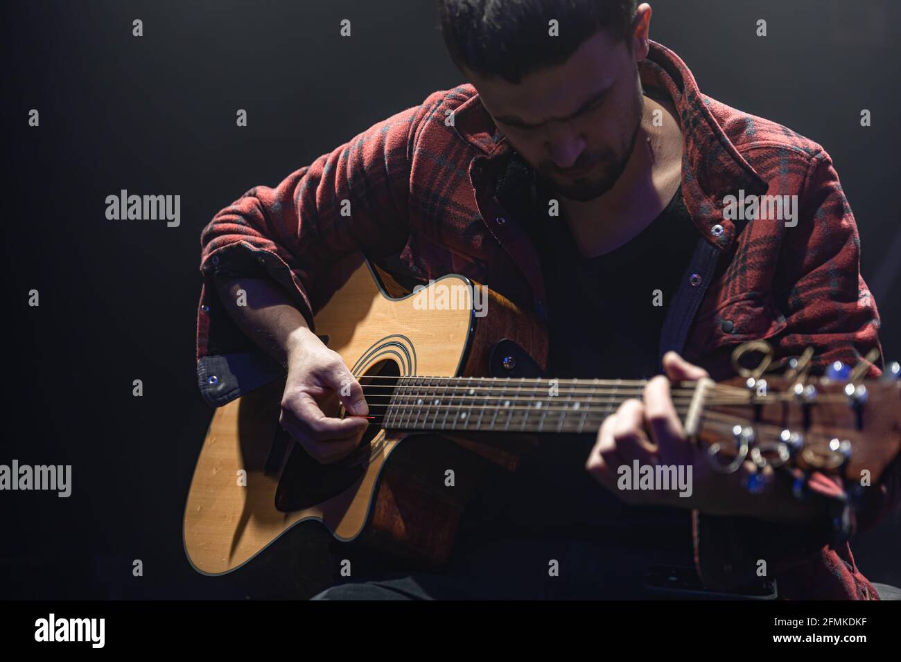 The musician plays the guitar while sitting in a dark room Stock Photo ...