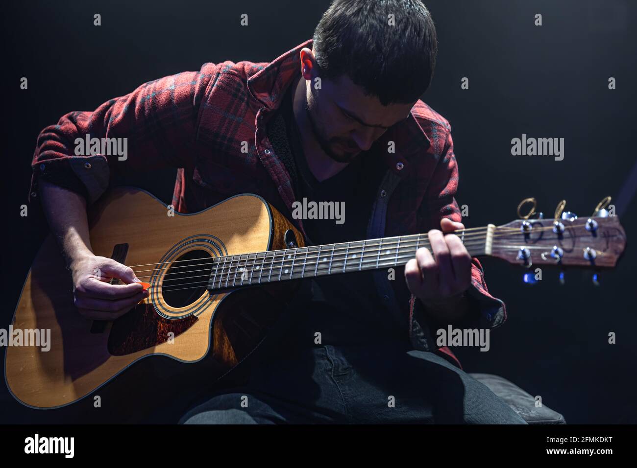 The musician plays the guitar while sitting in a dark room Stock Photo ...