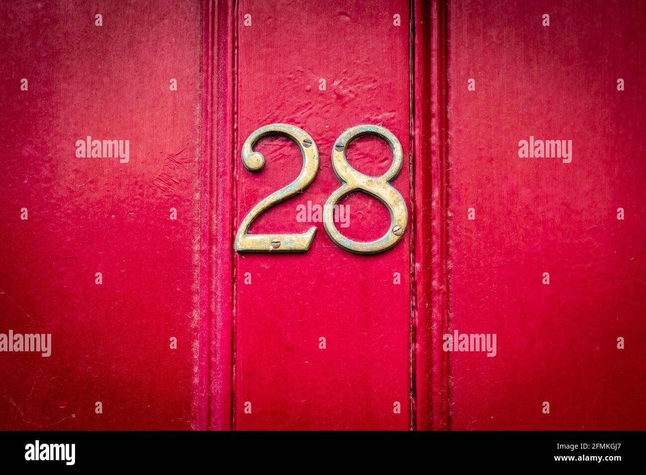 House number 28 on a dark rd wooden front door Stock Photo - Alamy