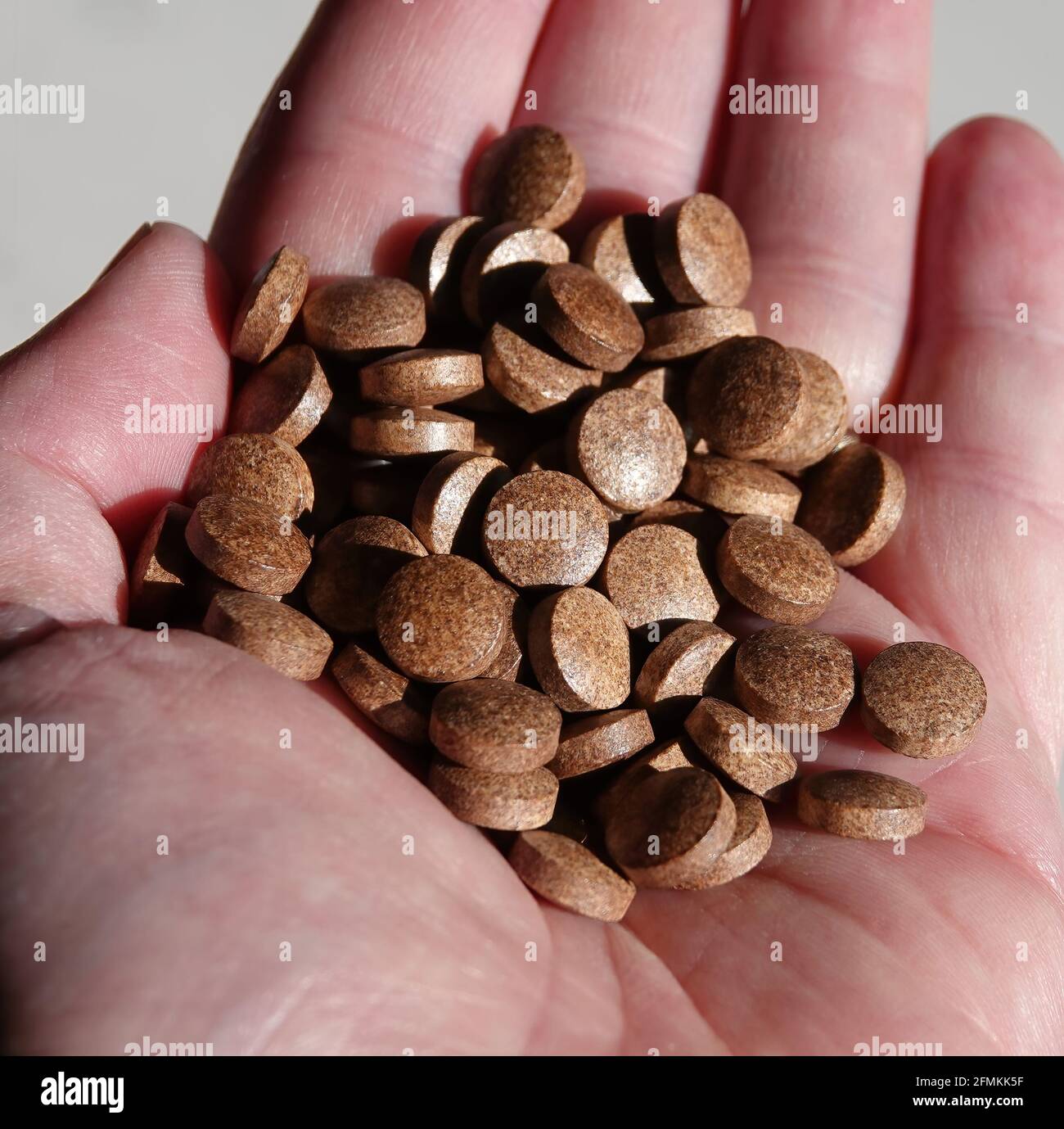 Closeup of a palm holding a heap of brown multivitamin tablets Stock ...