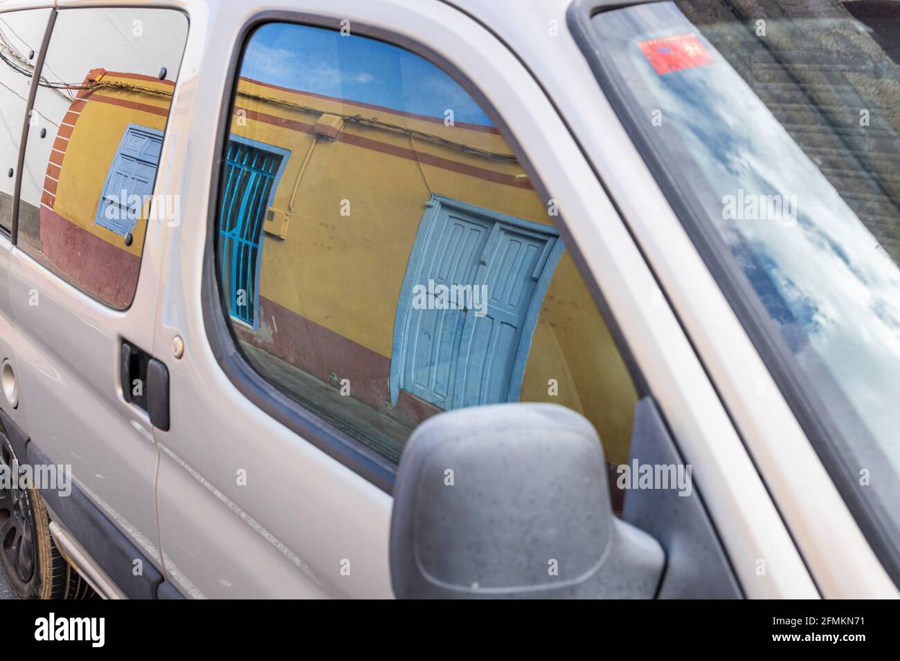 Reflection in van windows of a pastel painted house in Guia de Isora ...