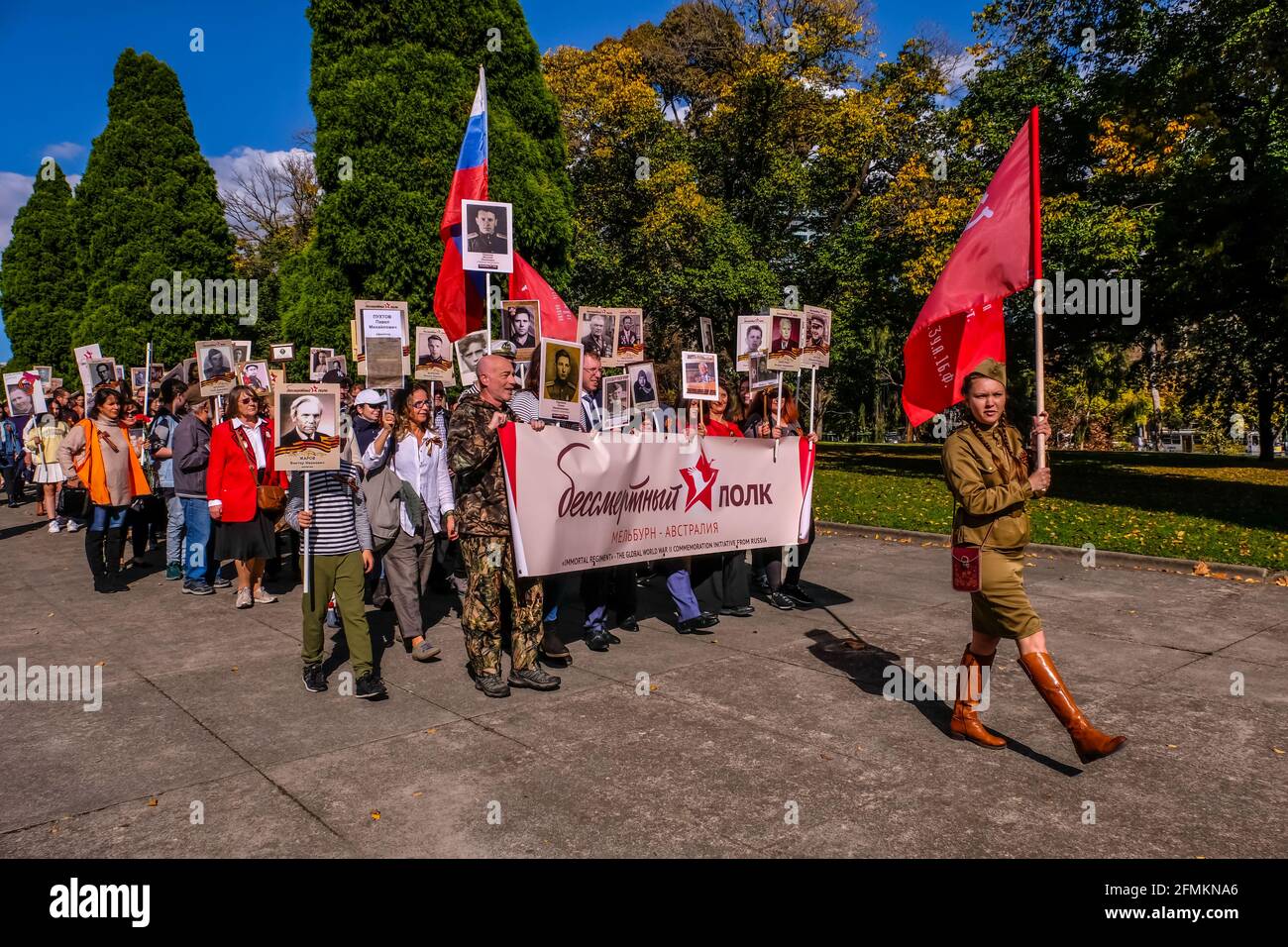 Participants are seen walking in a group with flags, a banner and ...