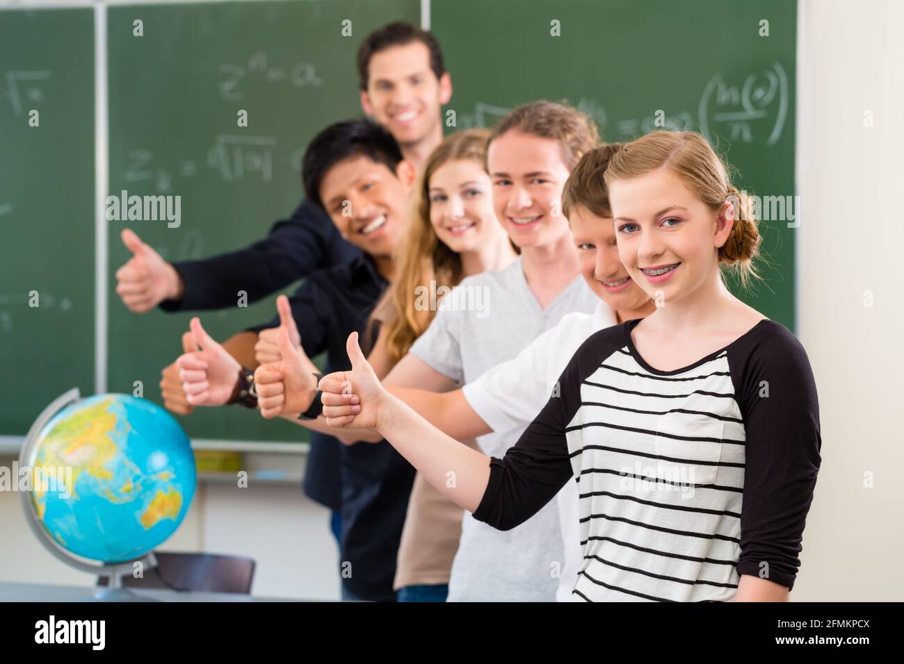 School class teacher and students stand in front of a blackboard with ...