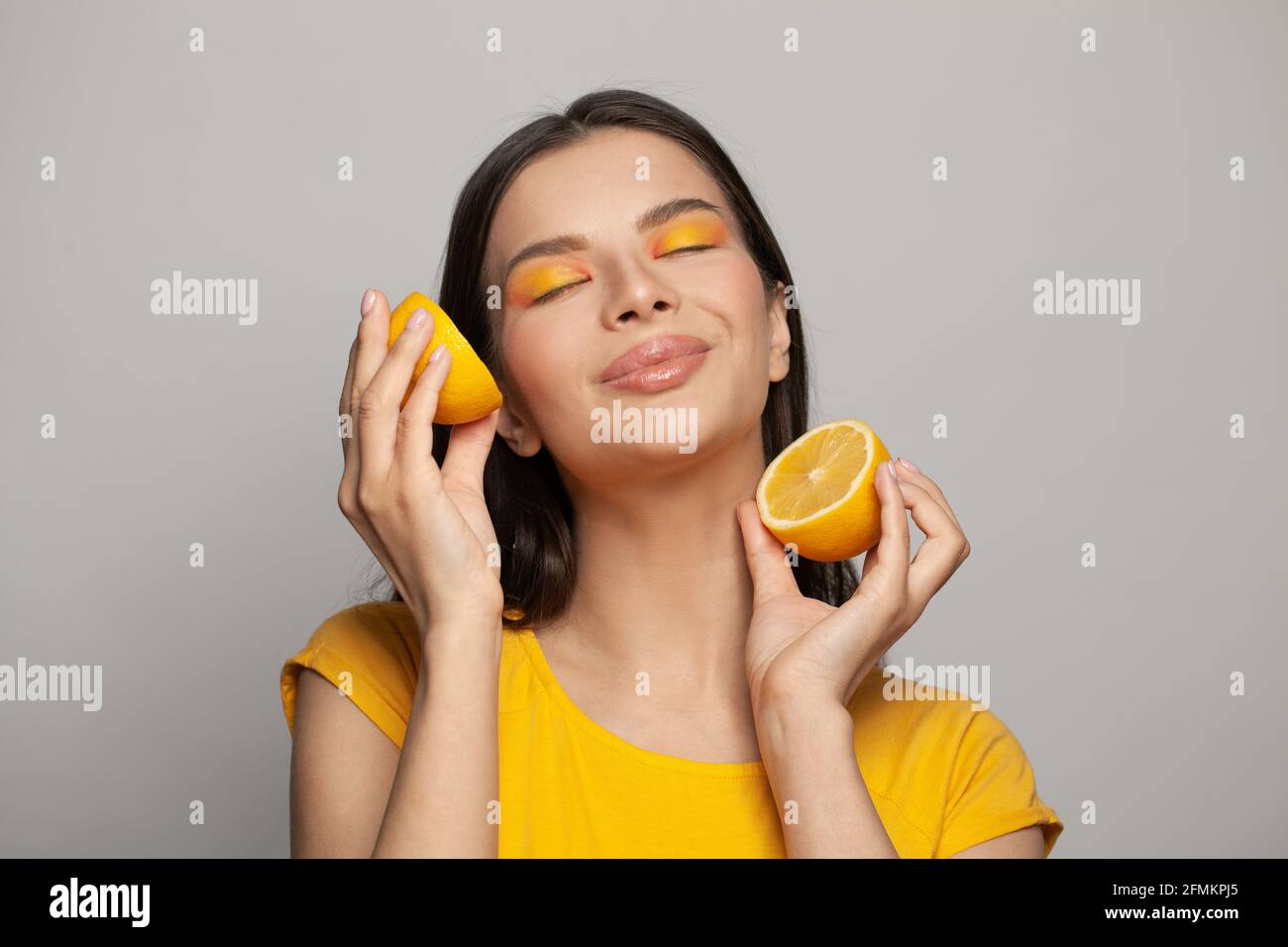 Attractive woman with clear skin enjoying lemon fruits on white ...