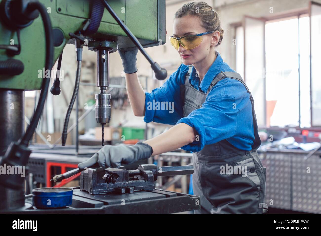 Woman worker in metal workshop greasing drill Stock Photo - Alamy