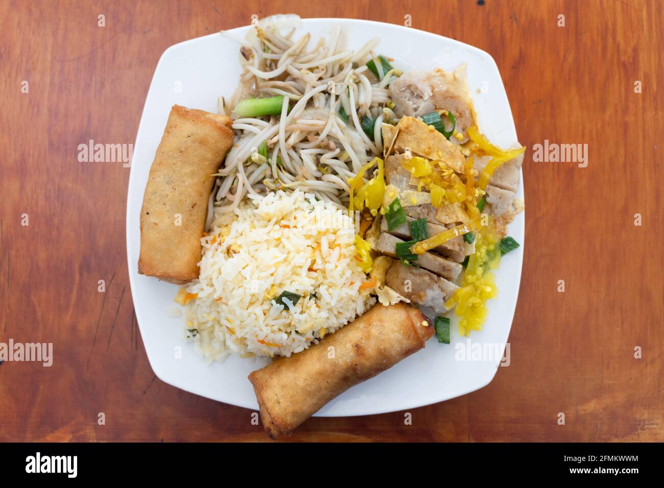 Top view of fried rice with spring rolls, meat pieces, spicy peppers ...