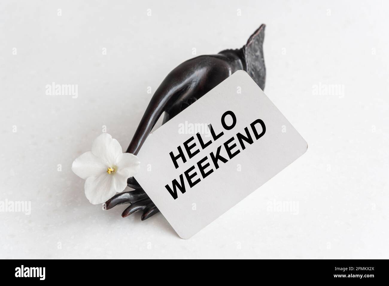 Hello Weekend Word on white card paper and flower in black hand. Office ...