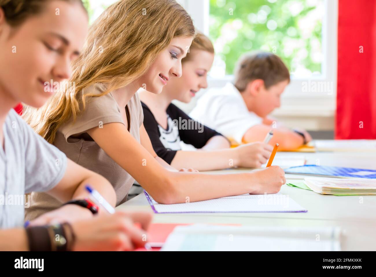 Students or pupils of school class writing an exam test in classroom ...