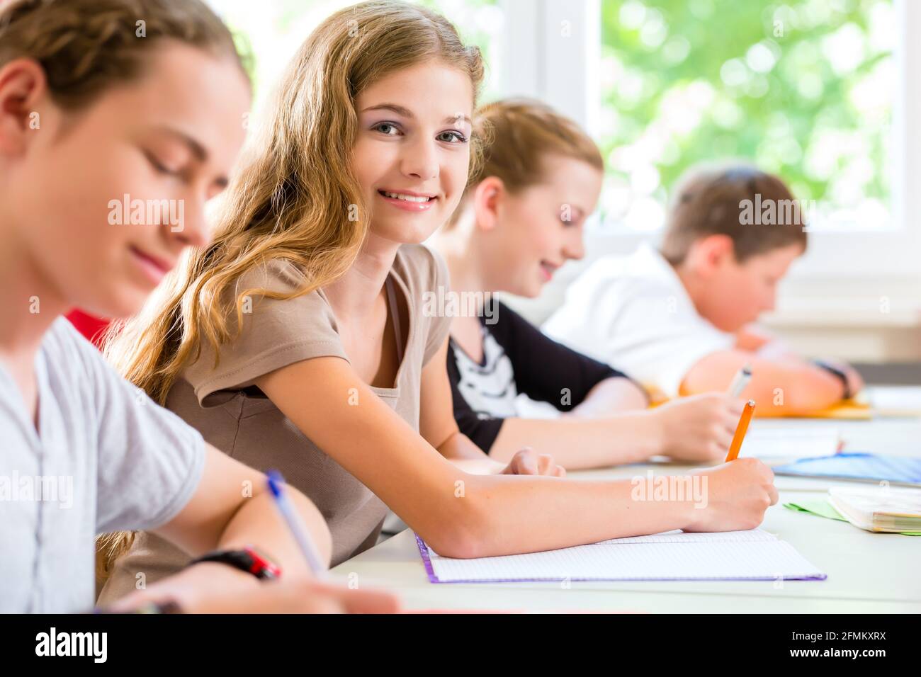 Students or pupils of school class writing an exam test in classroom ...