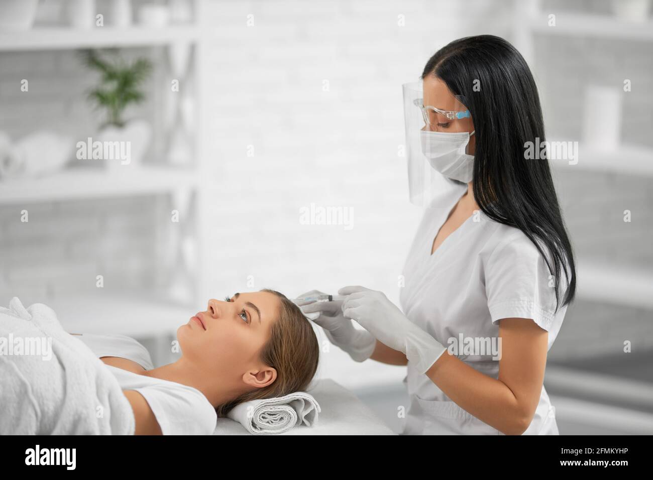 Side view of brunette young beautician sitting and doing special ...