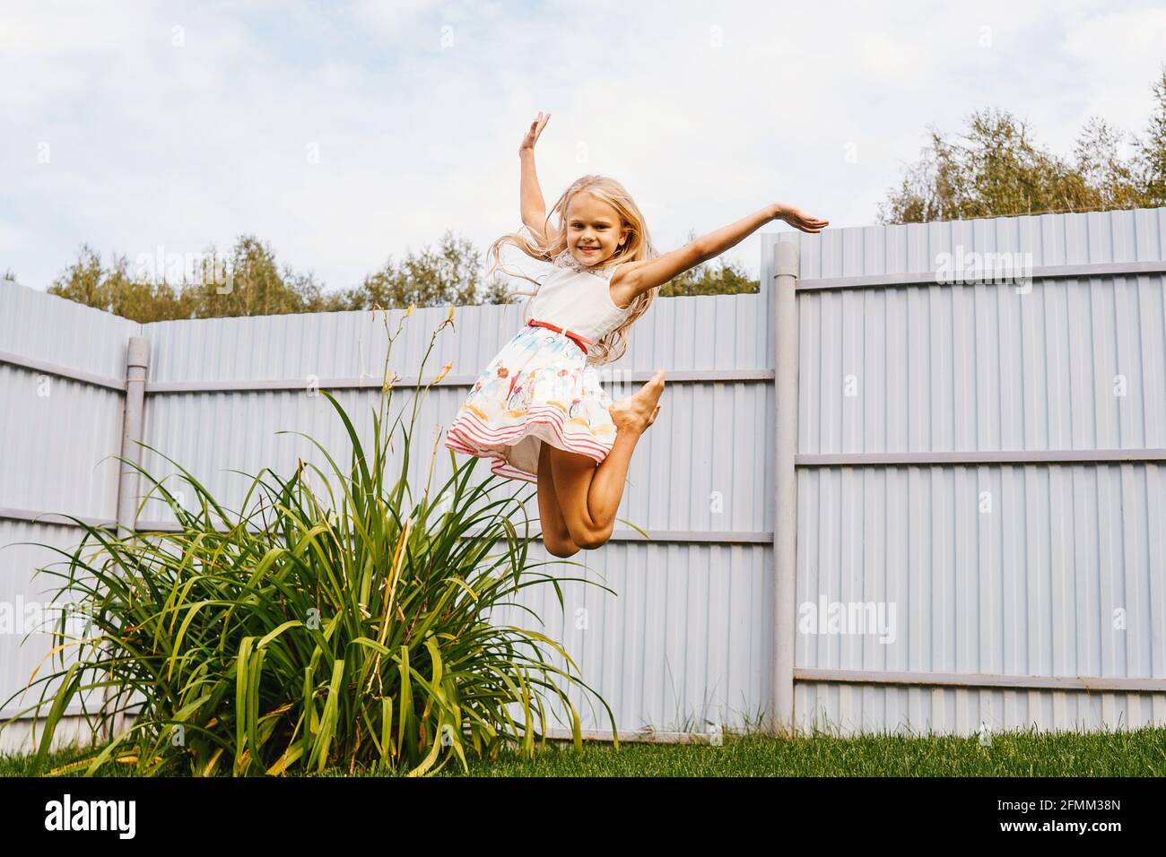 Happy childhood: Little girl having fun and jump on grass Stock Photo ...