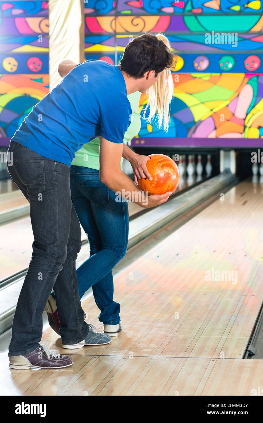 Young couple or friends, man and woman, playing bowling with a ball in ...