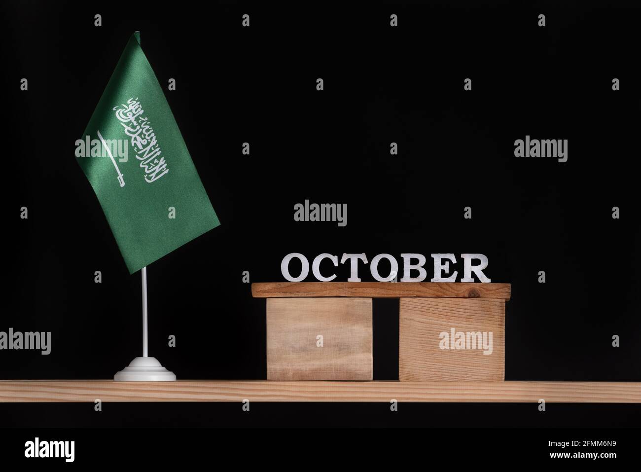 Wooden calendar of October with Saudi Arabia flag on black background ...