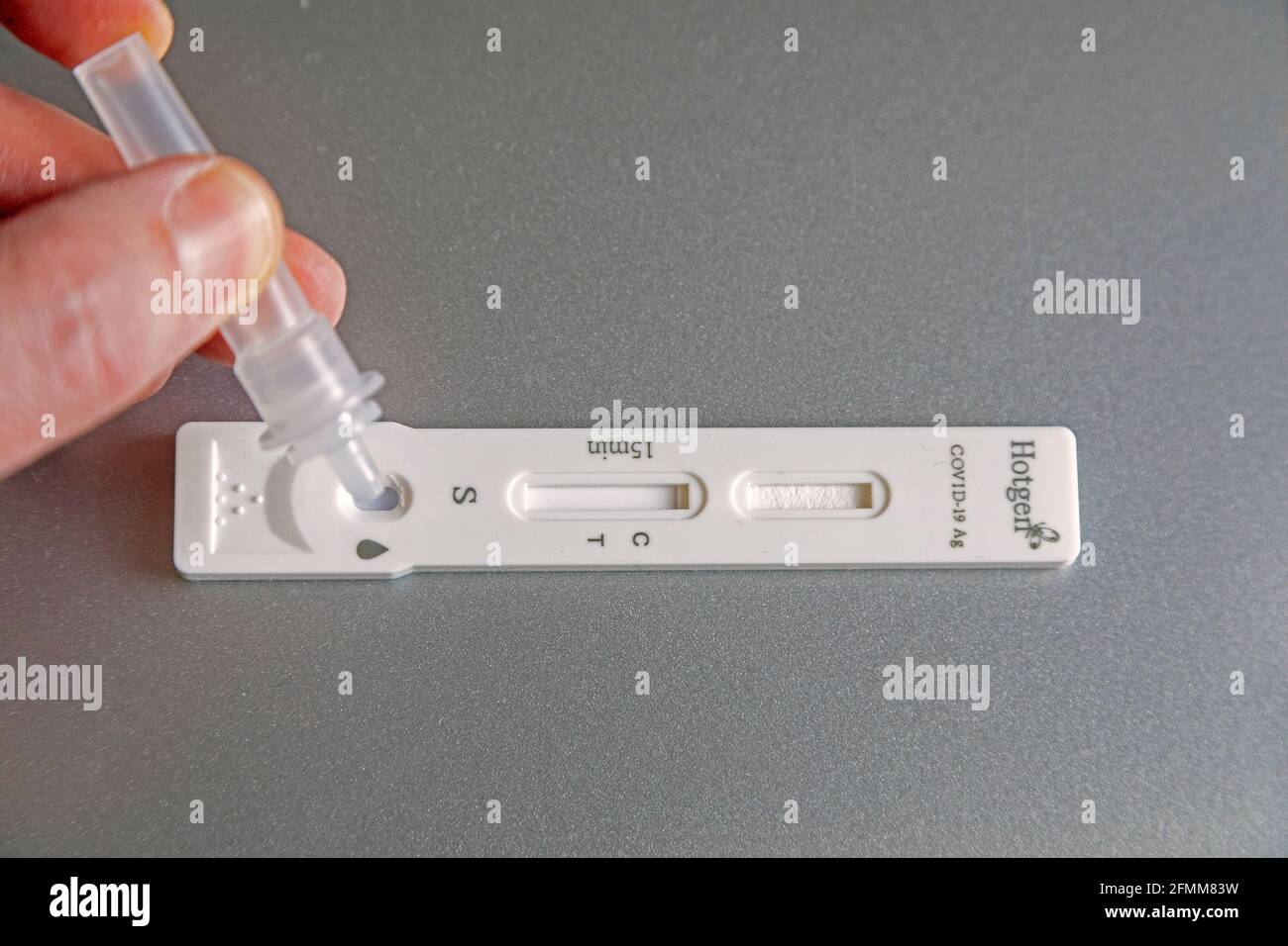 A test sample is dropped onto a Covid-19 antigen testing strip Stock ...