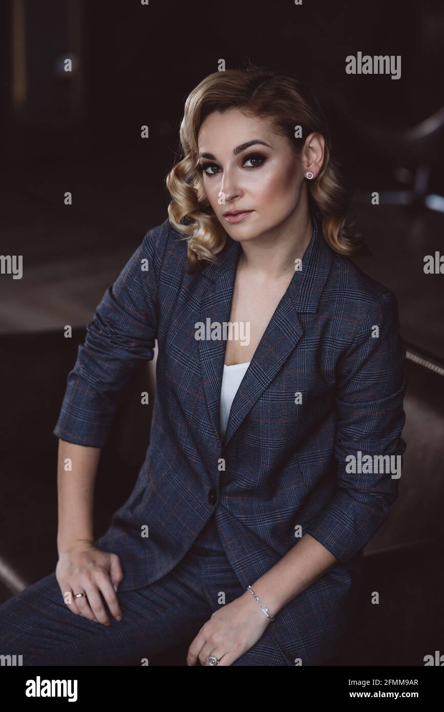 Portrait of a confident beautiful business woman in a suit on a dark background. The concept of ...