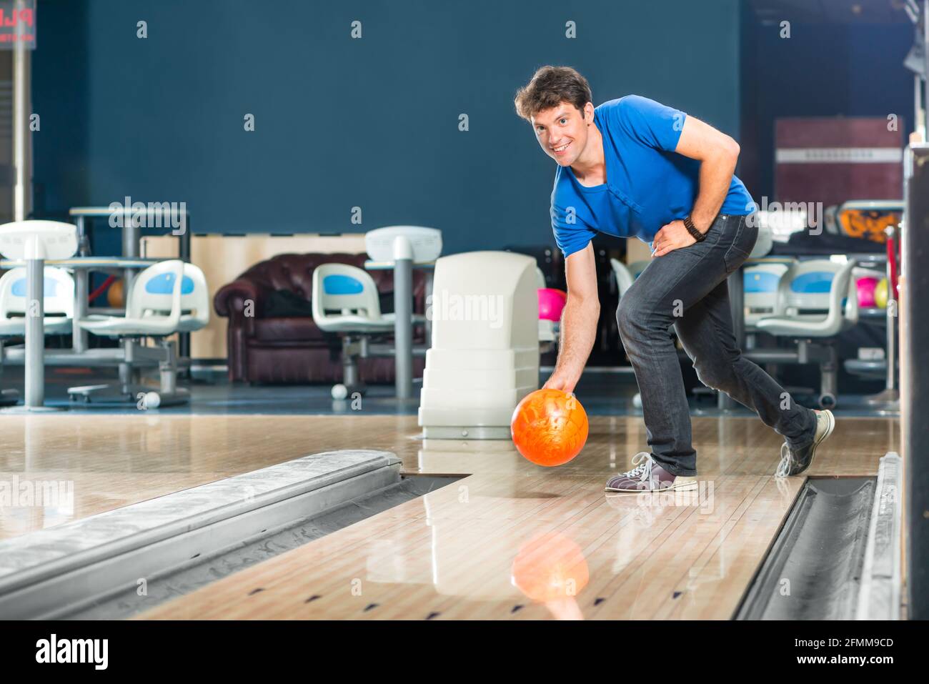 Young man in bowling alley having fun, the sporty man playing a bowling ...