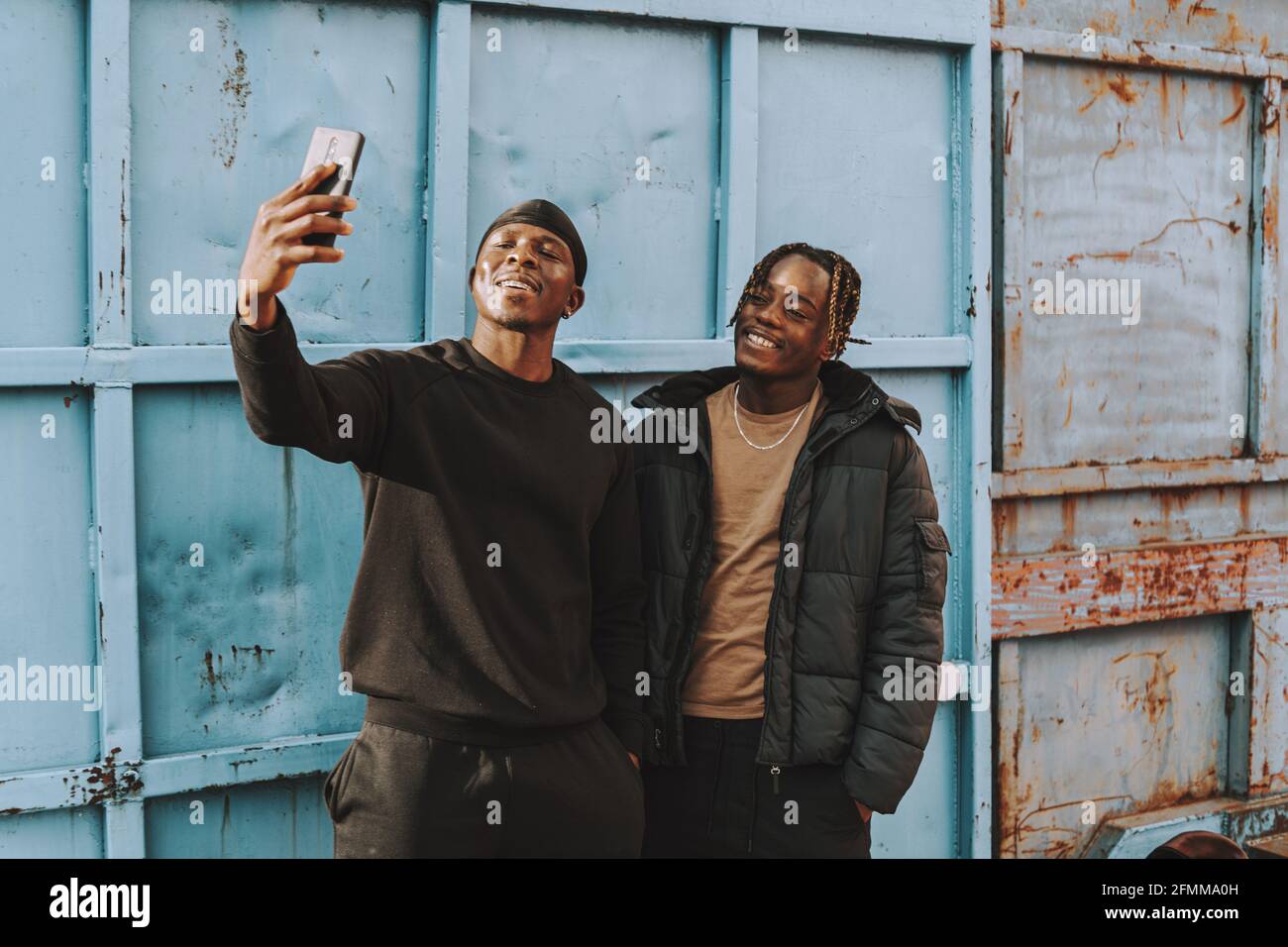 Happy smiling Black Spanish male friends taking a selfie in front of a ...
