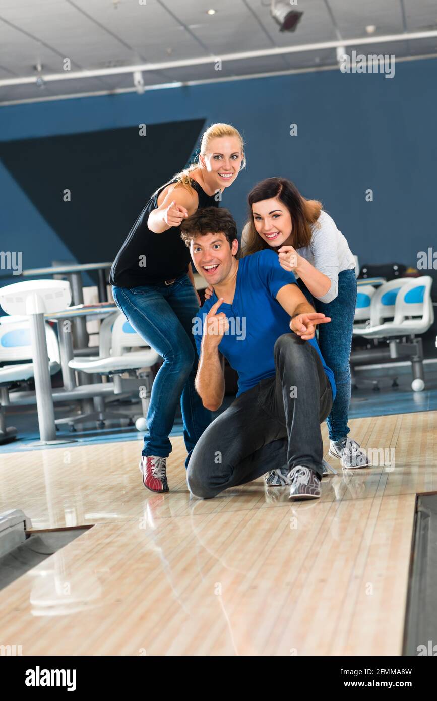 Group of friends in a bowling alley having fun, the girls cheering then ...