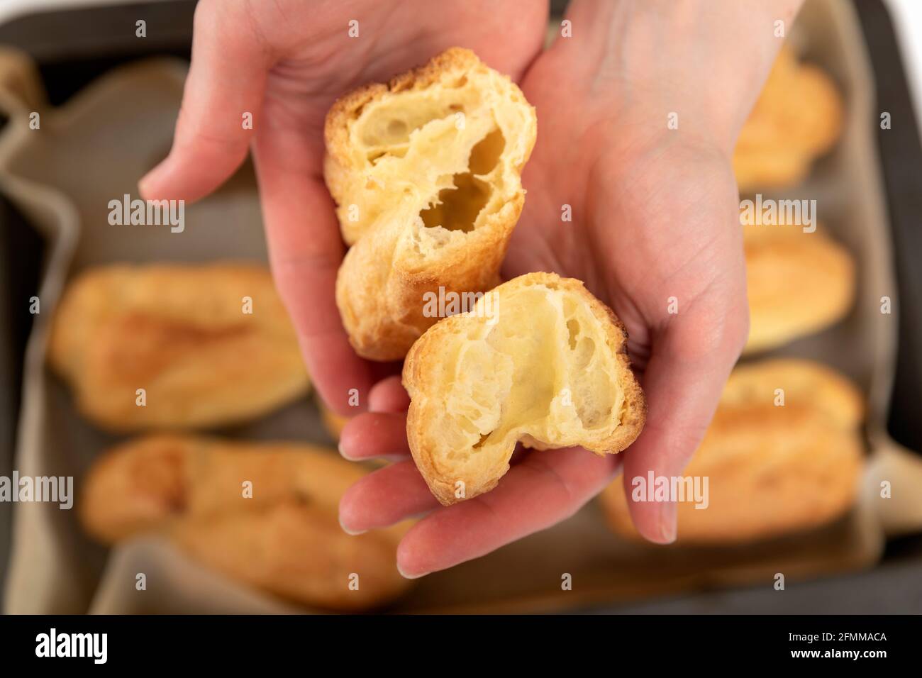 Middle of workpiece for profiteroles in hands of Chef. Puffs, popovers ...