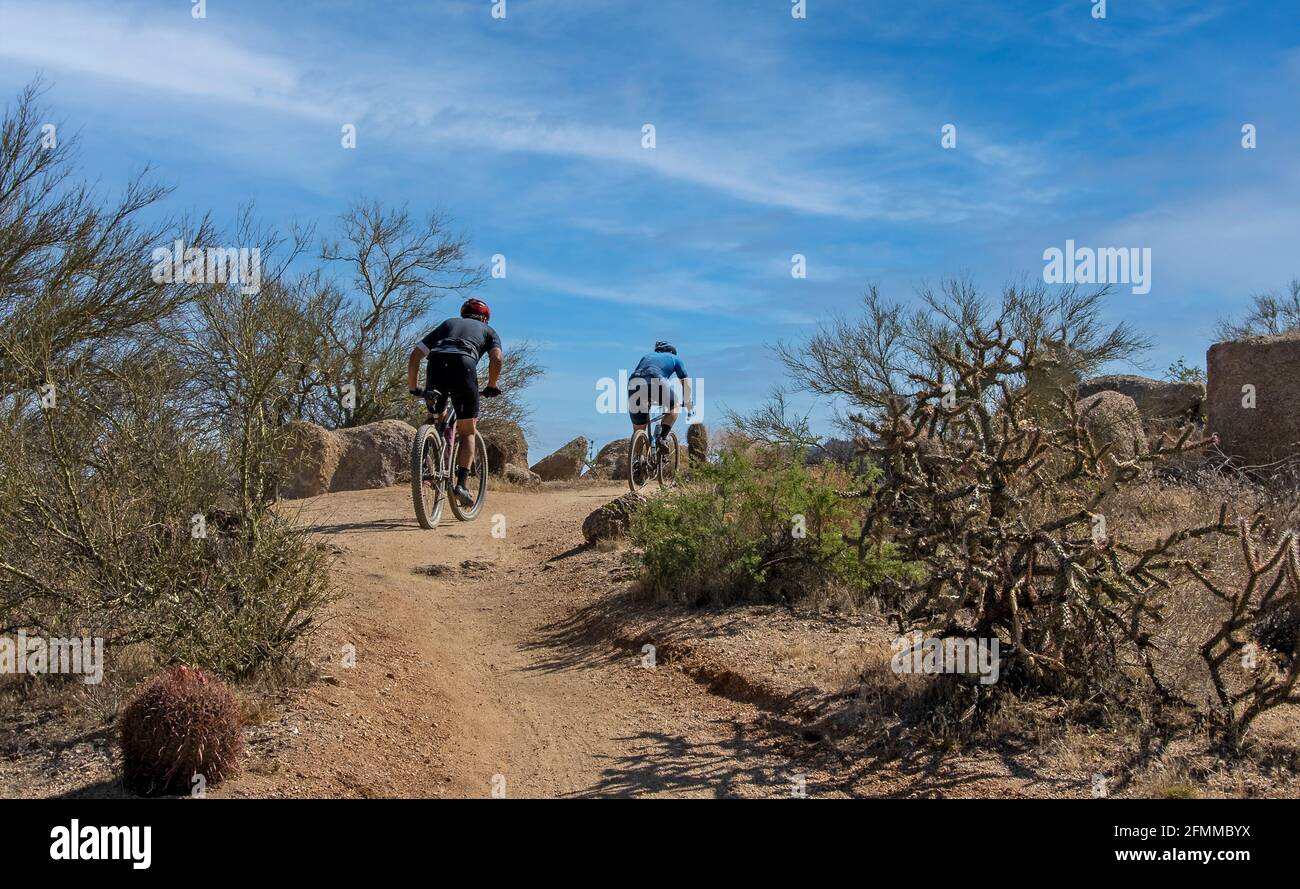 Landscape image of 2 mountain bikers riding up a desert trail in North ...