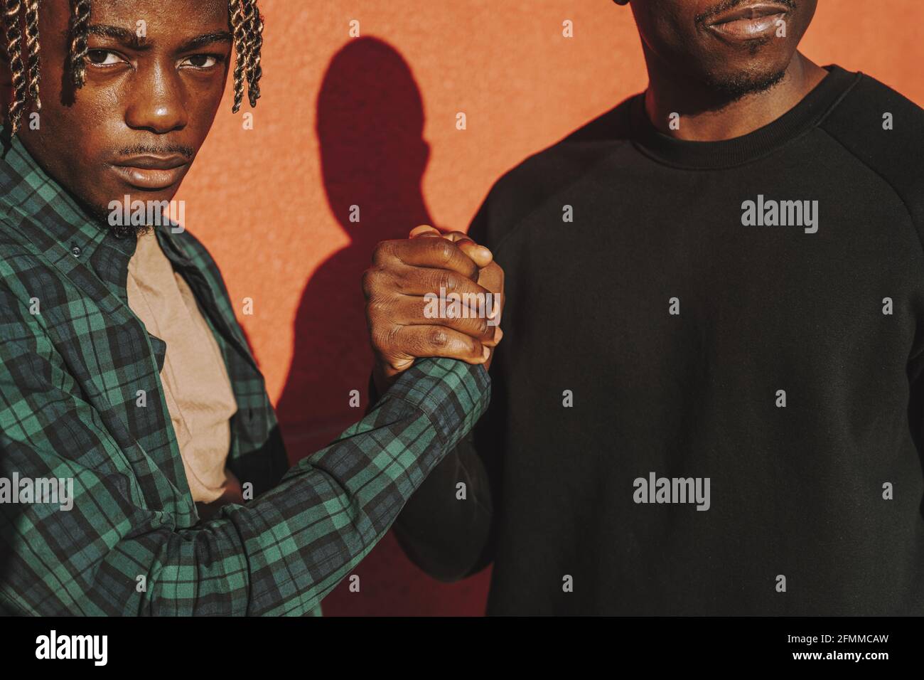 Black Spanish male friends meeting and greeting with a handshake ...