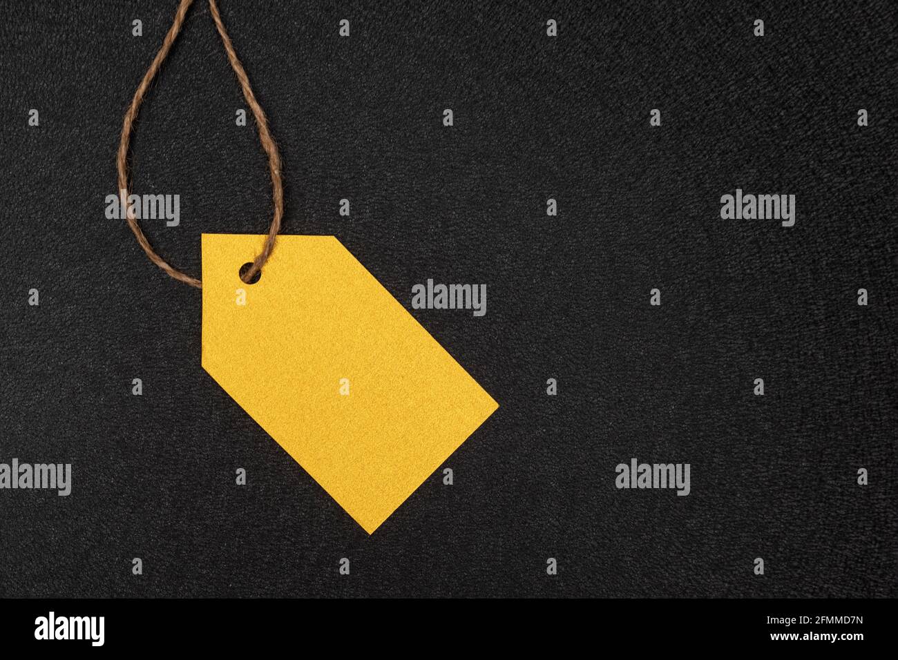 Yellow clothing tag on black background. Label blank mockup template ...