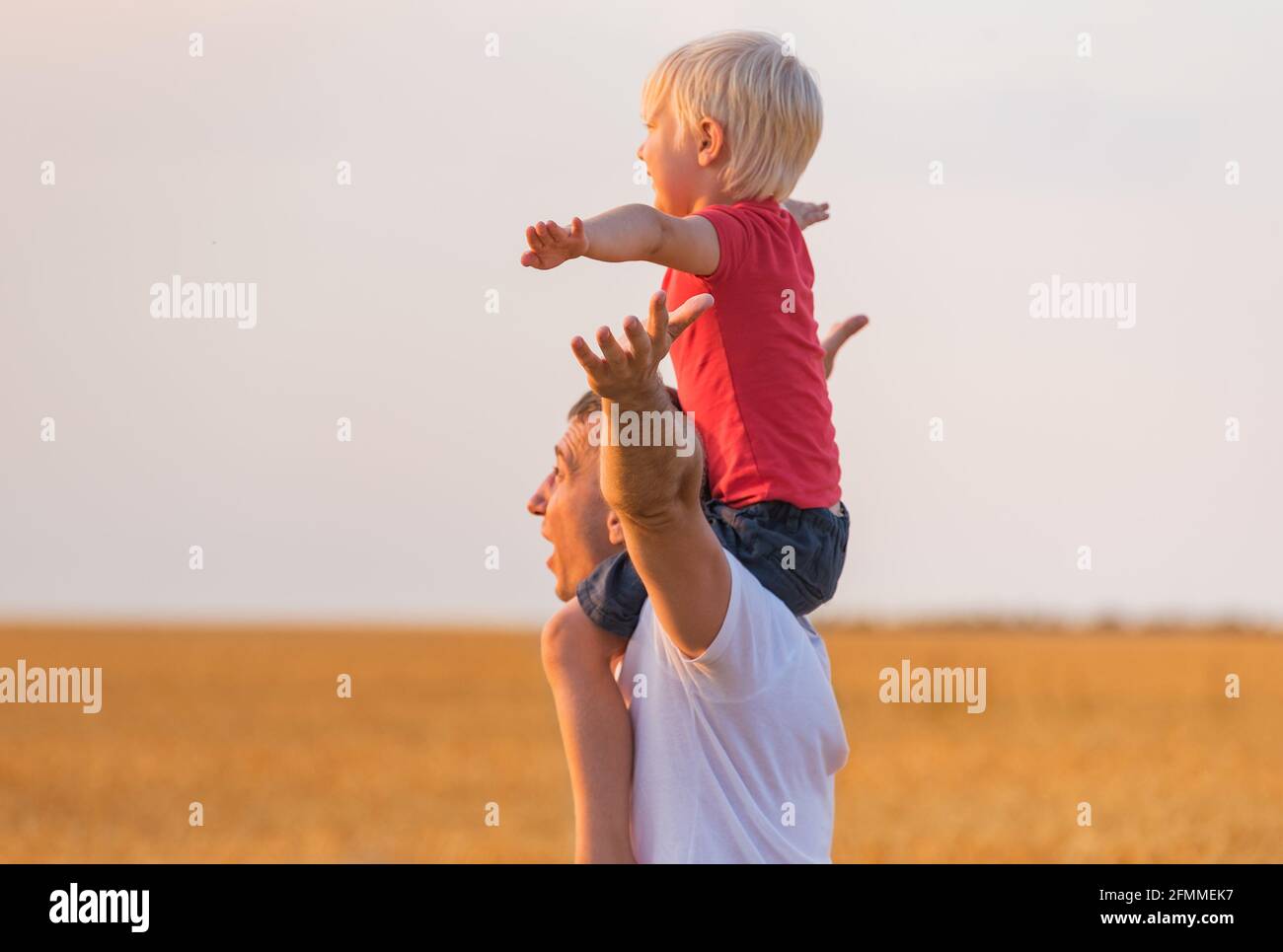 Child sits on fathers shoulders and hands up. Happy fatherhood Stock ...