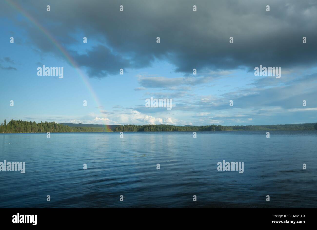 Rainbow and rain over a swedish lake a summers day Stock Photo - Alamy