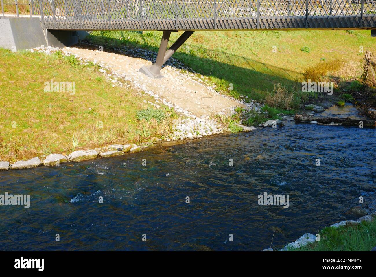 metal footbridge in the sunlight over a blue river in the shade Stock ...