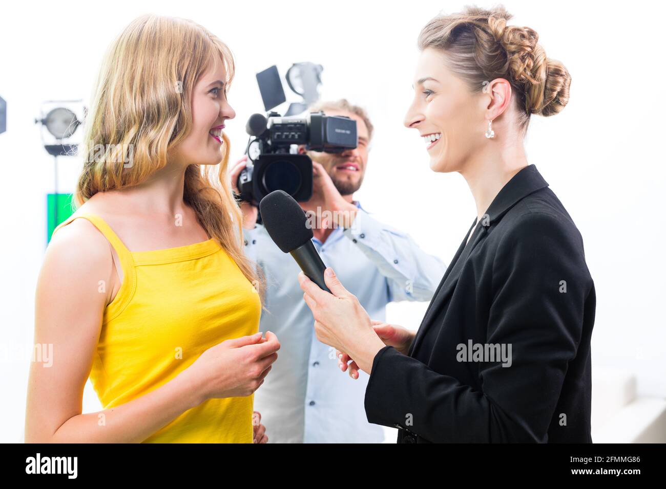 Reporter and cameraman film shoot actress interview on film set for TV ...