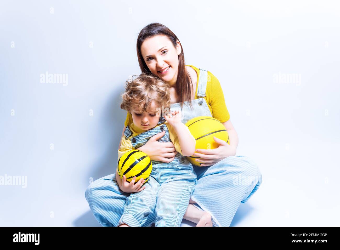Single parent young adult mother playing with her son with a basketball ...
