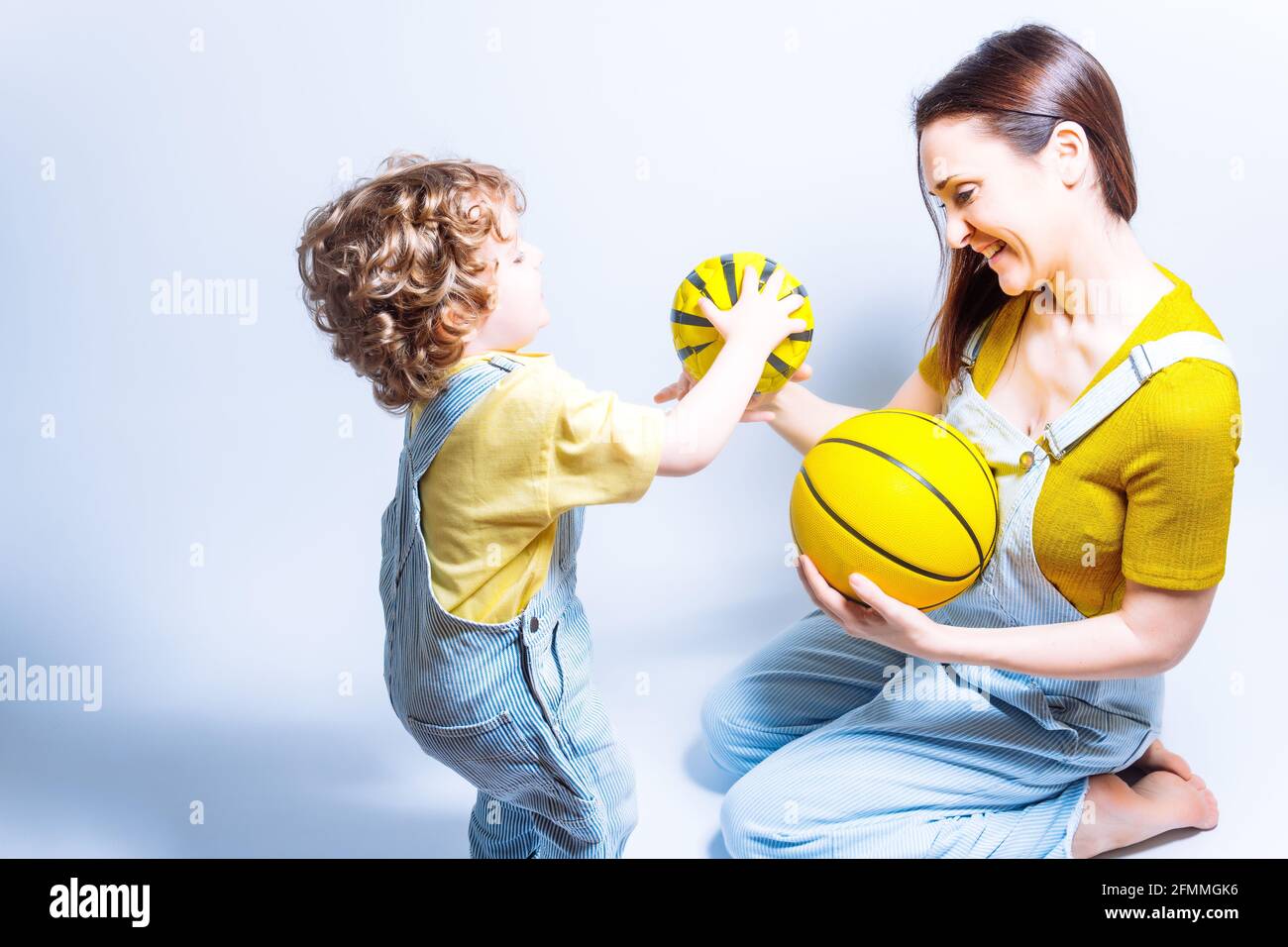 Single parent young adult mother playing with her son with a basketball ...