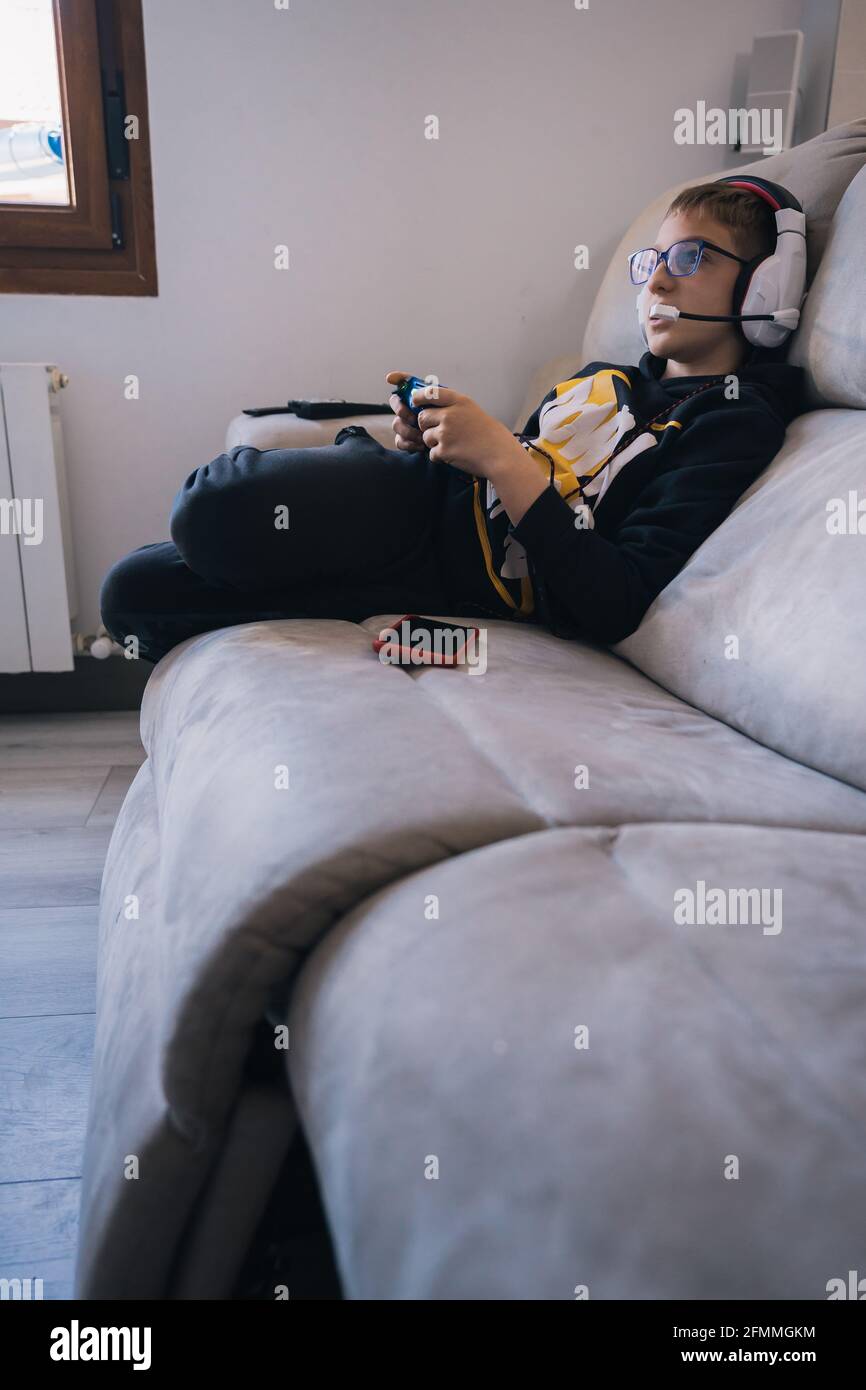 Spanish little boy playing an online videogame sitting on a sofa Stock ...