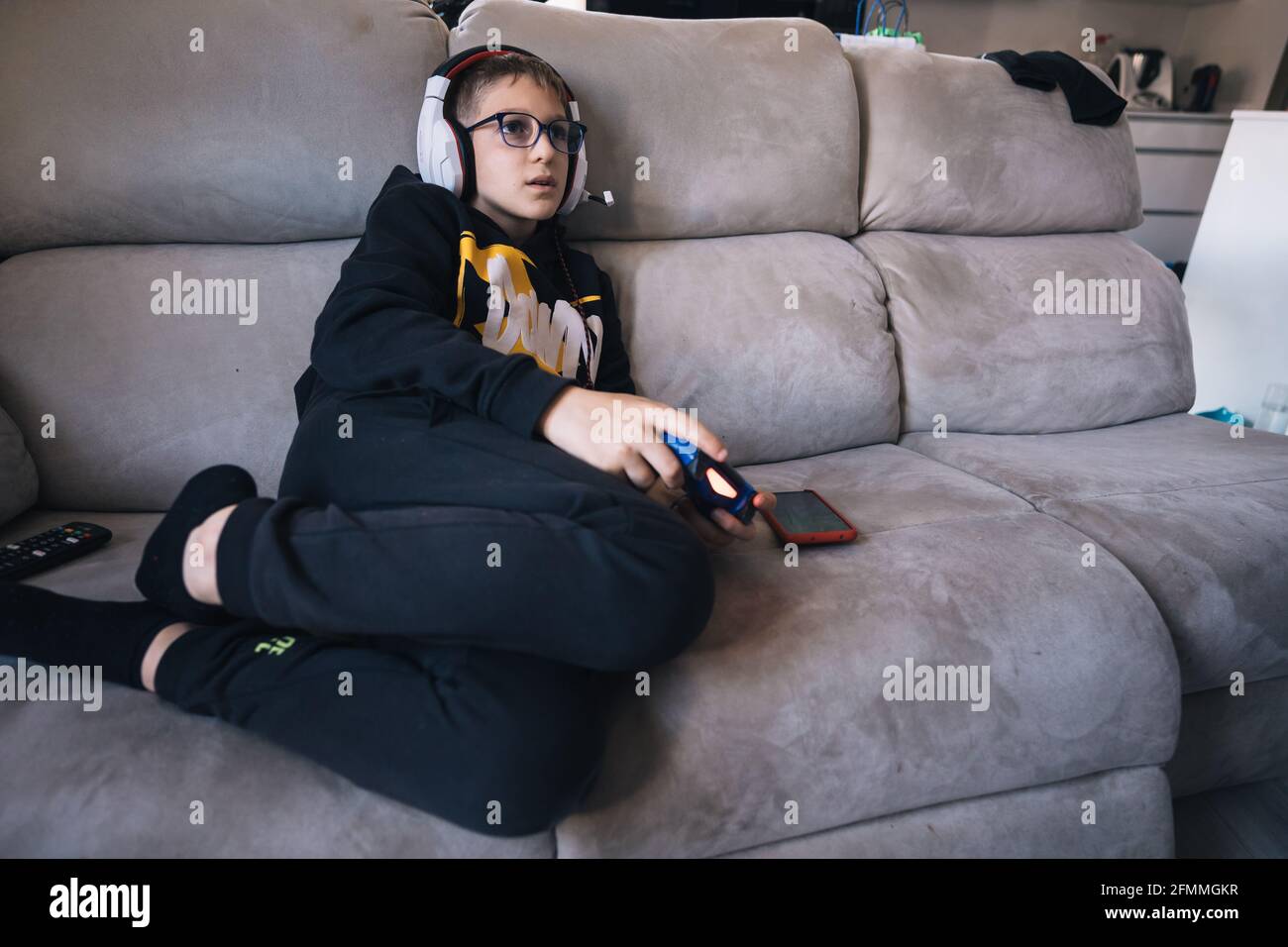 Spanish little boy playing an online videogame sitting on a sofa Stock ...